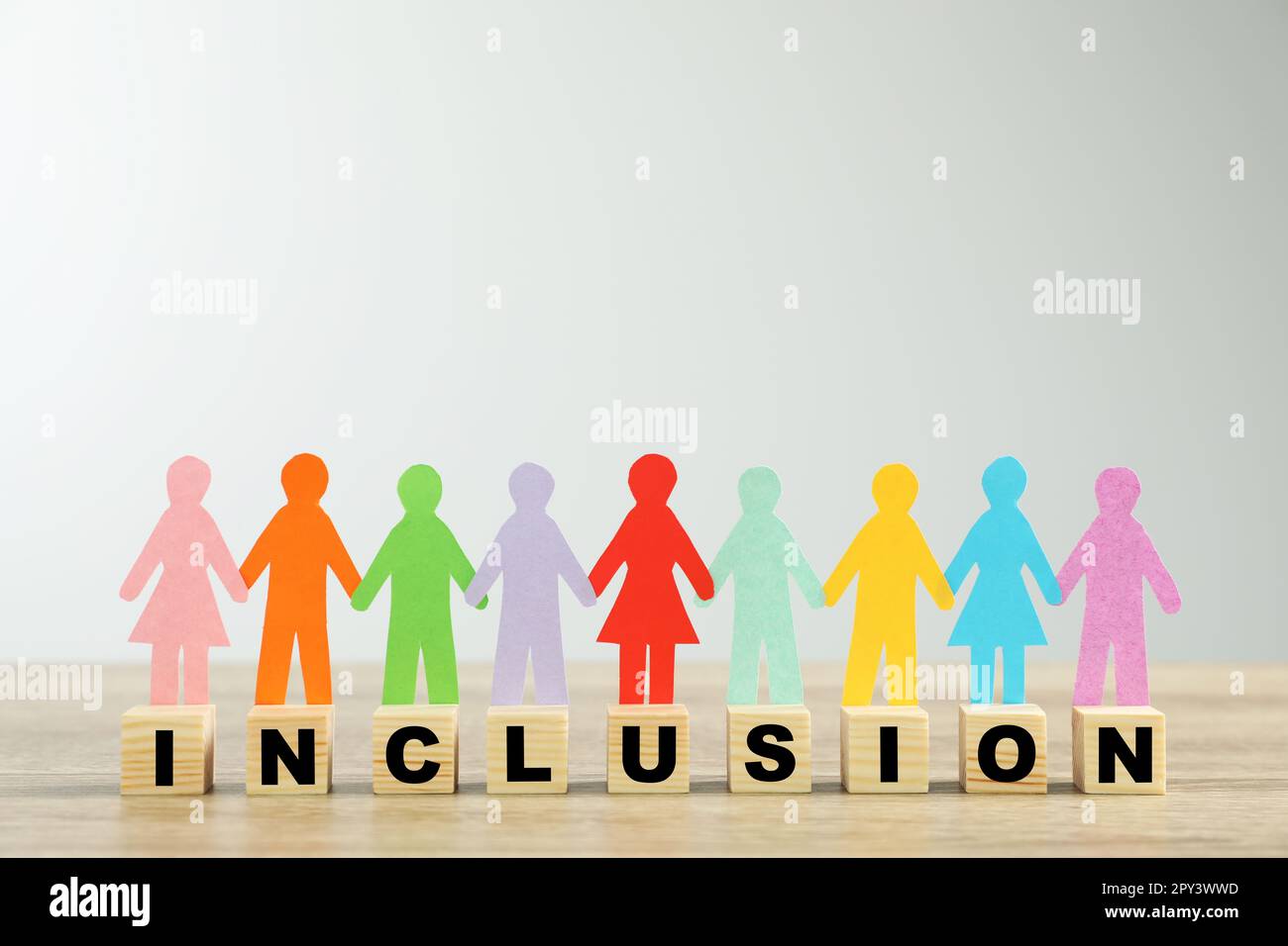 Paper human figures and wooden cubes with word Inclusion on table ...