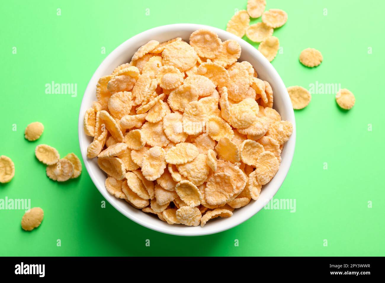 Bowl of tasty crispy corn flakes on light green background, flat lay ...