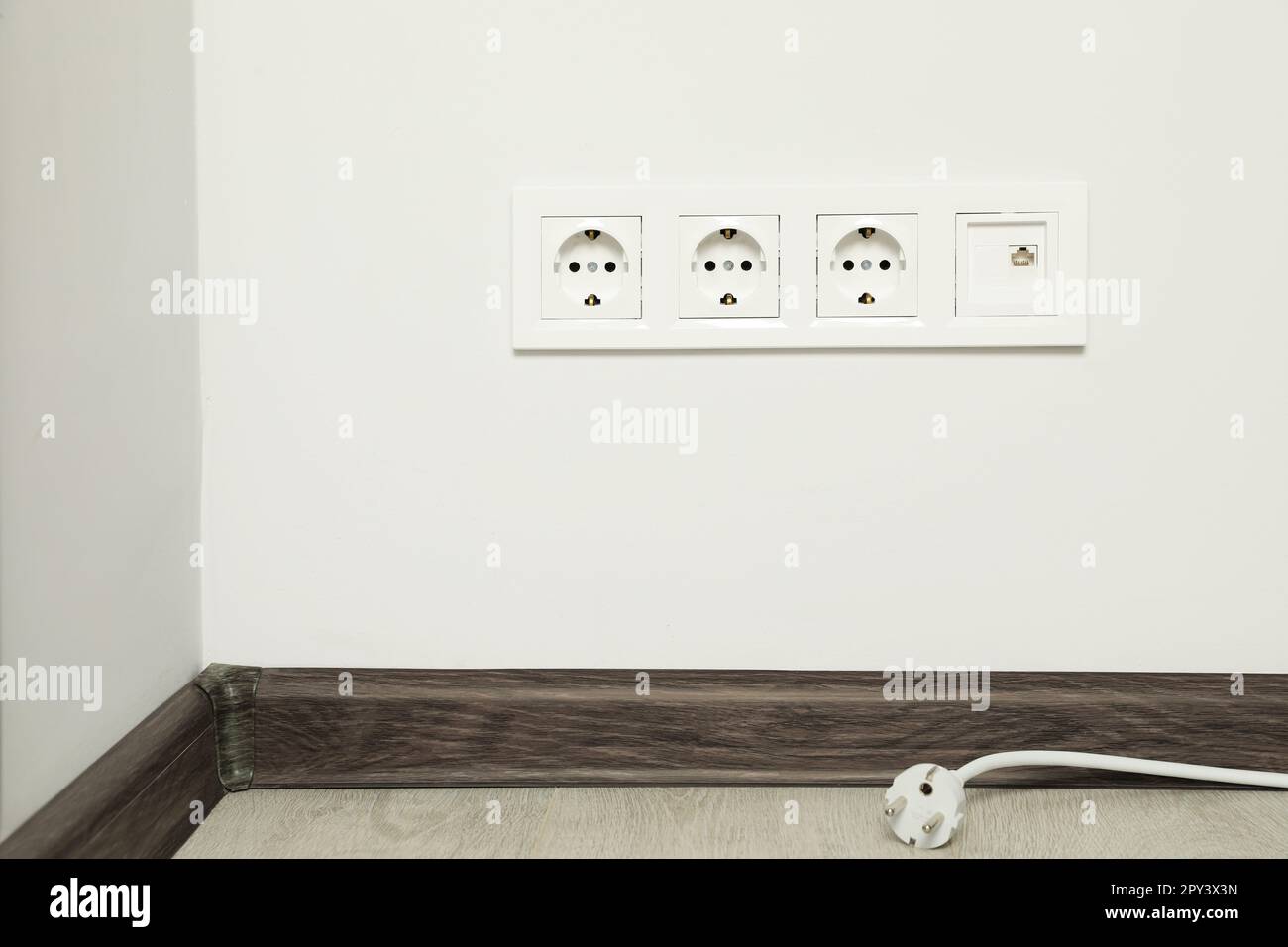 Plug near white wall with power sockets indoors. Electrical supply ...