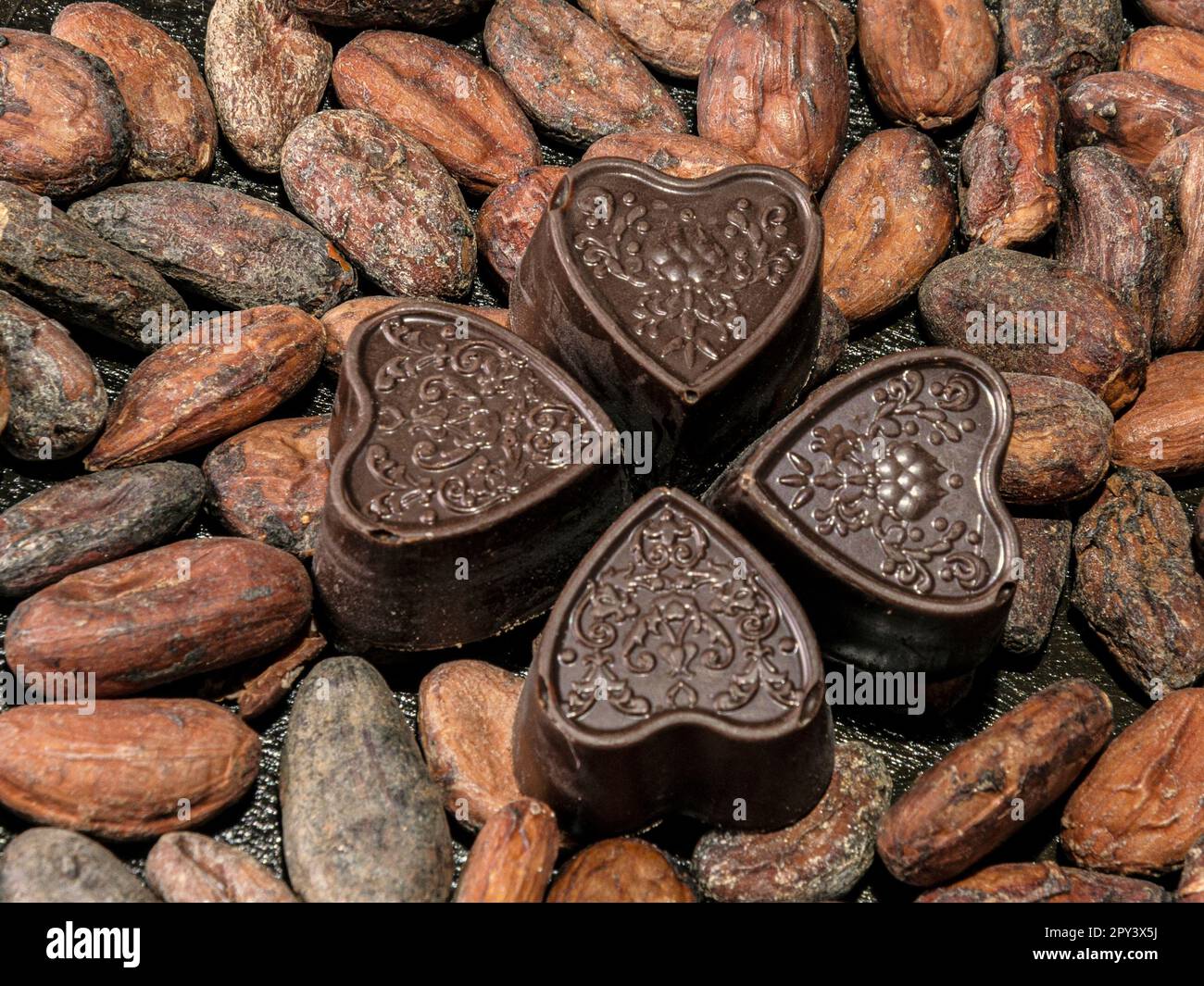 Four chocolates in the shape of a heart on a background of roasted ...