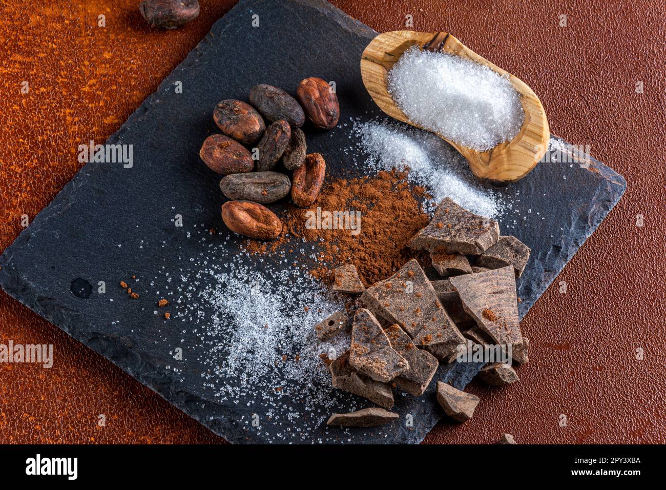 Pieces of chocolate and its ingredients, on a slate slab with rustic ...