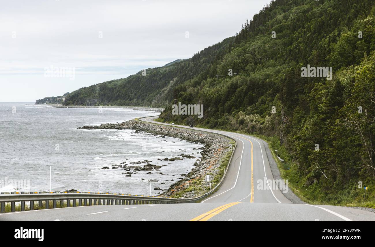 Aerial view of a curving coastal road traversing a verdant landscape ...