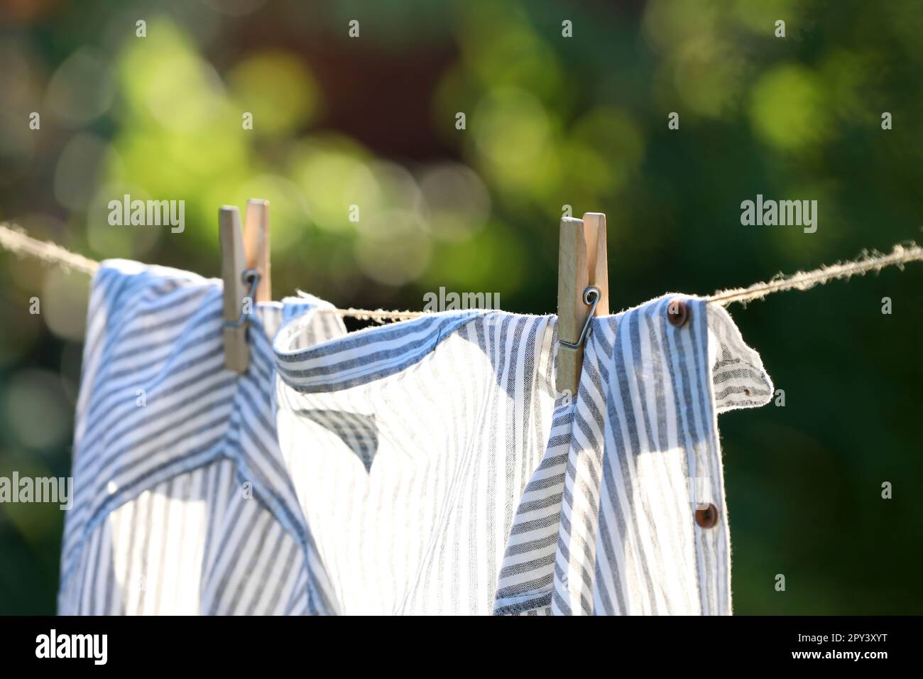 Washing line with drying shirt against blurred background, focus on clothespin Stock Photo - Alamy
