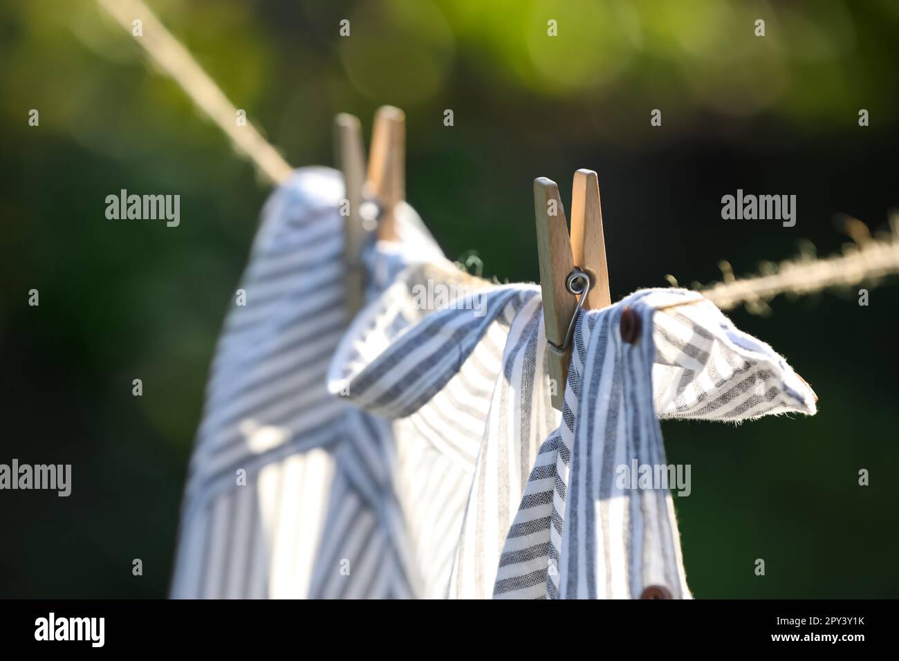 Washing line with drying shirt against blurred background, focus on ...