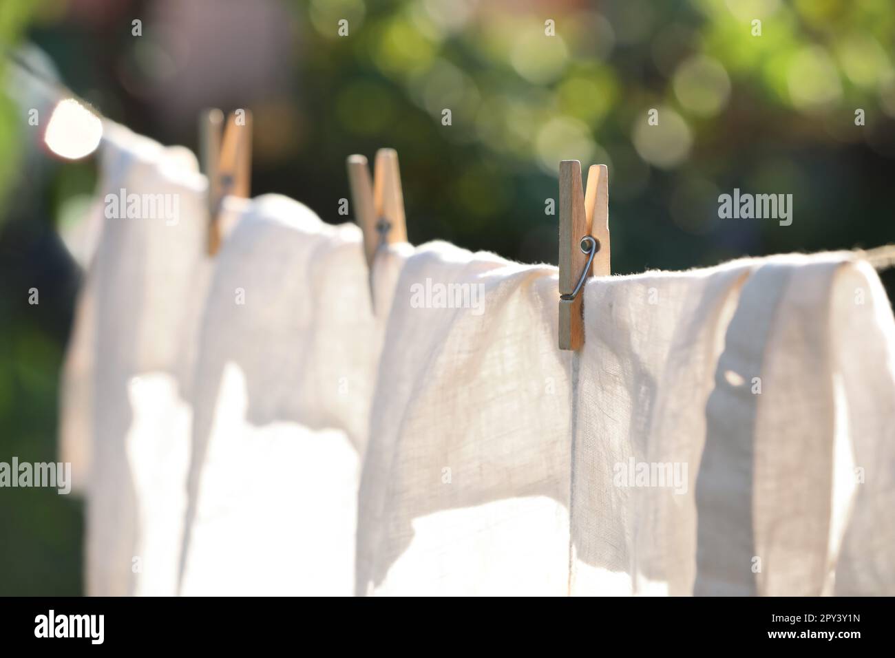 Washing line with drying shirt against blurred background, focus on ...