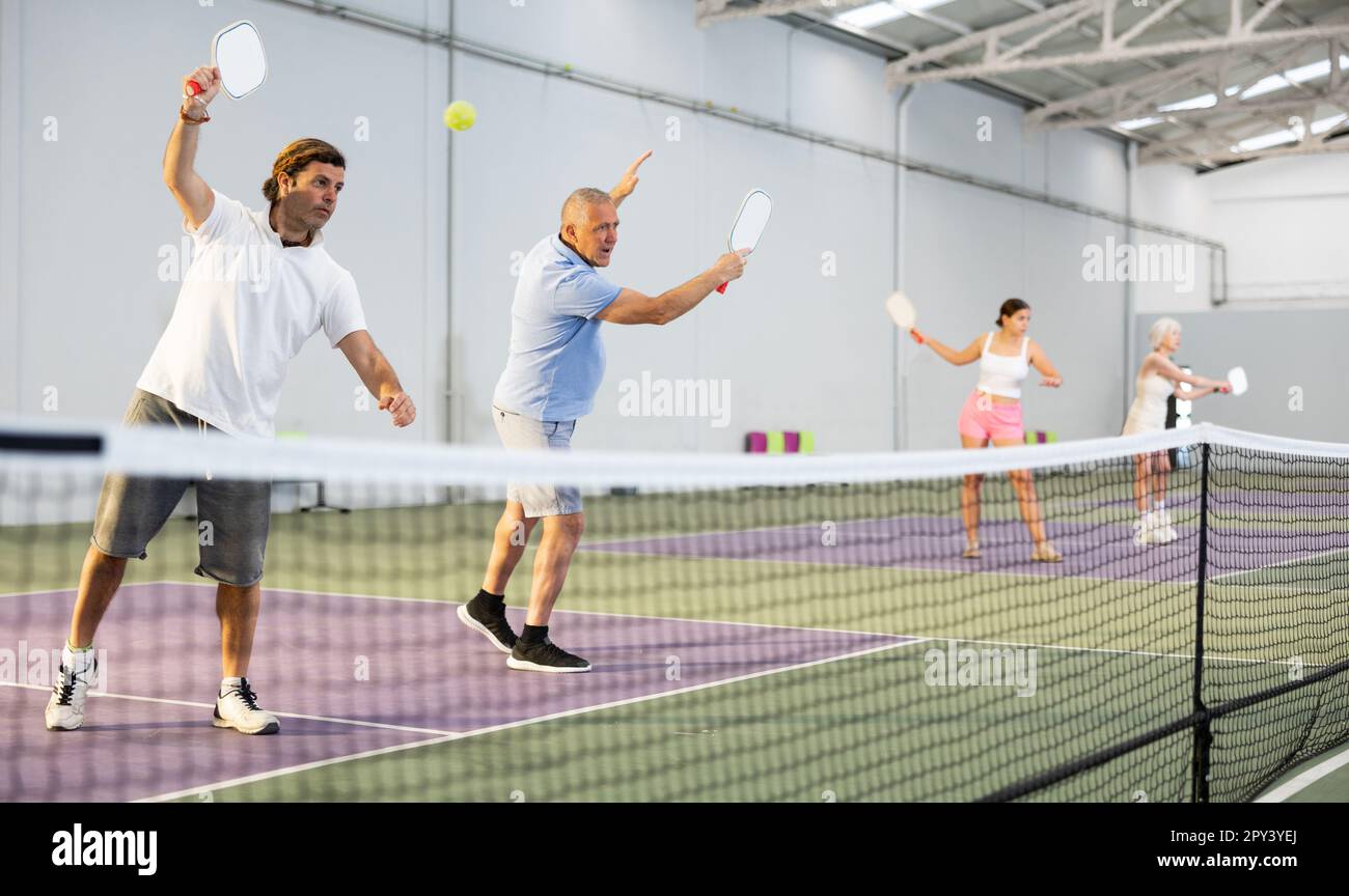 Adult man playing doubles pickleball with aged partner indoors Stock ...