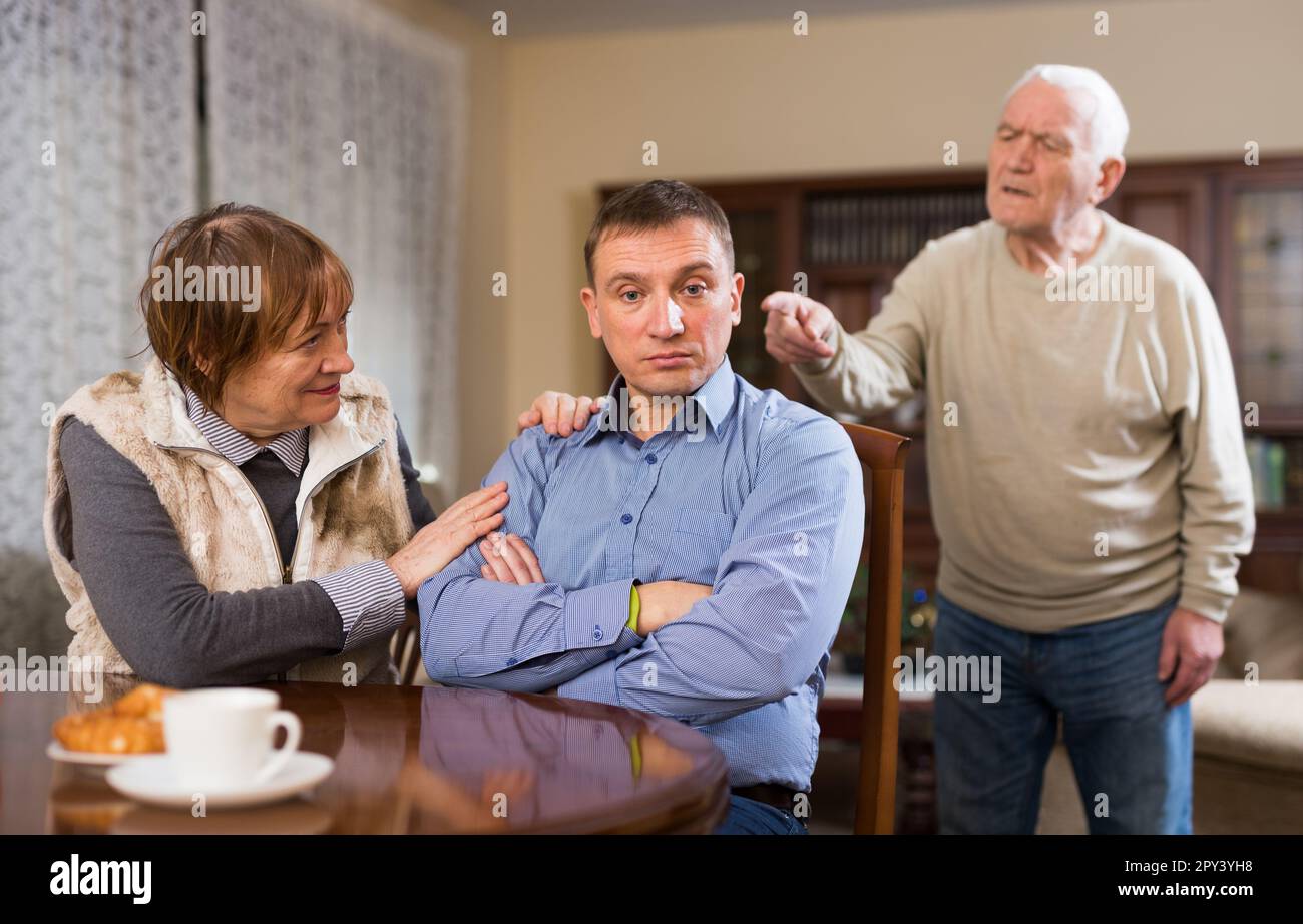 Mother calming adult son during quarrel with father Stock Photo - Alamy