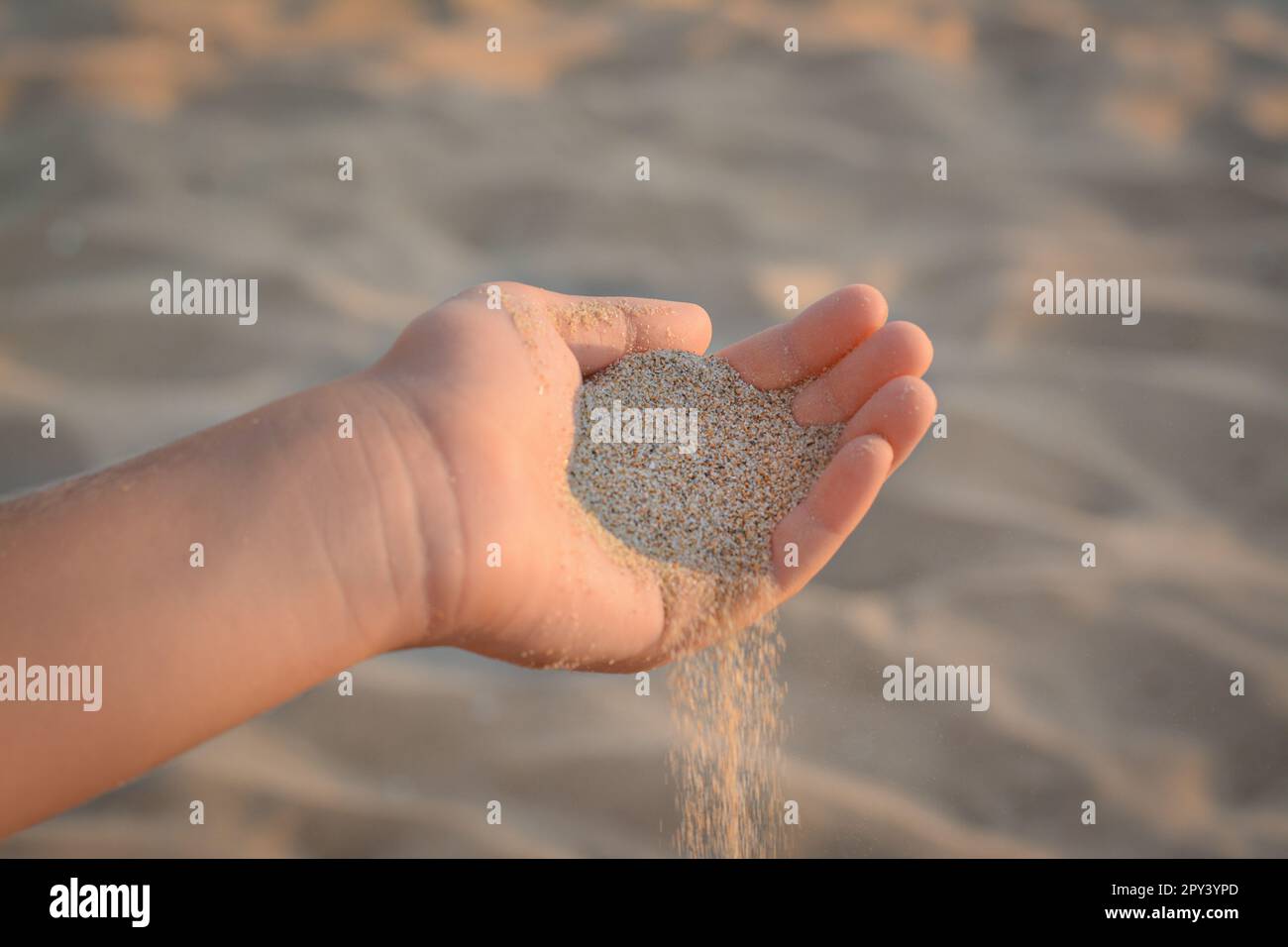 Girl pouring sand from hand outdoors, closeup. Fleeting time concept ...