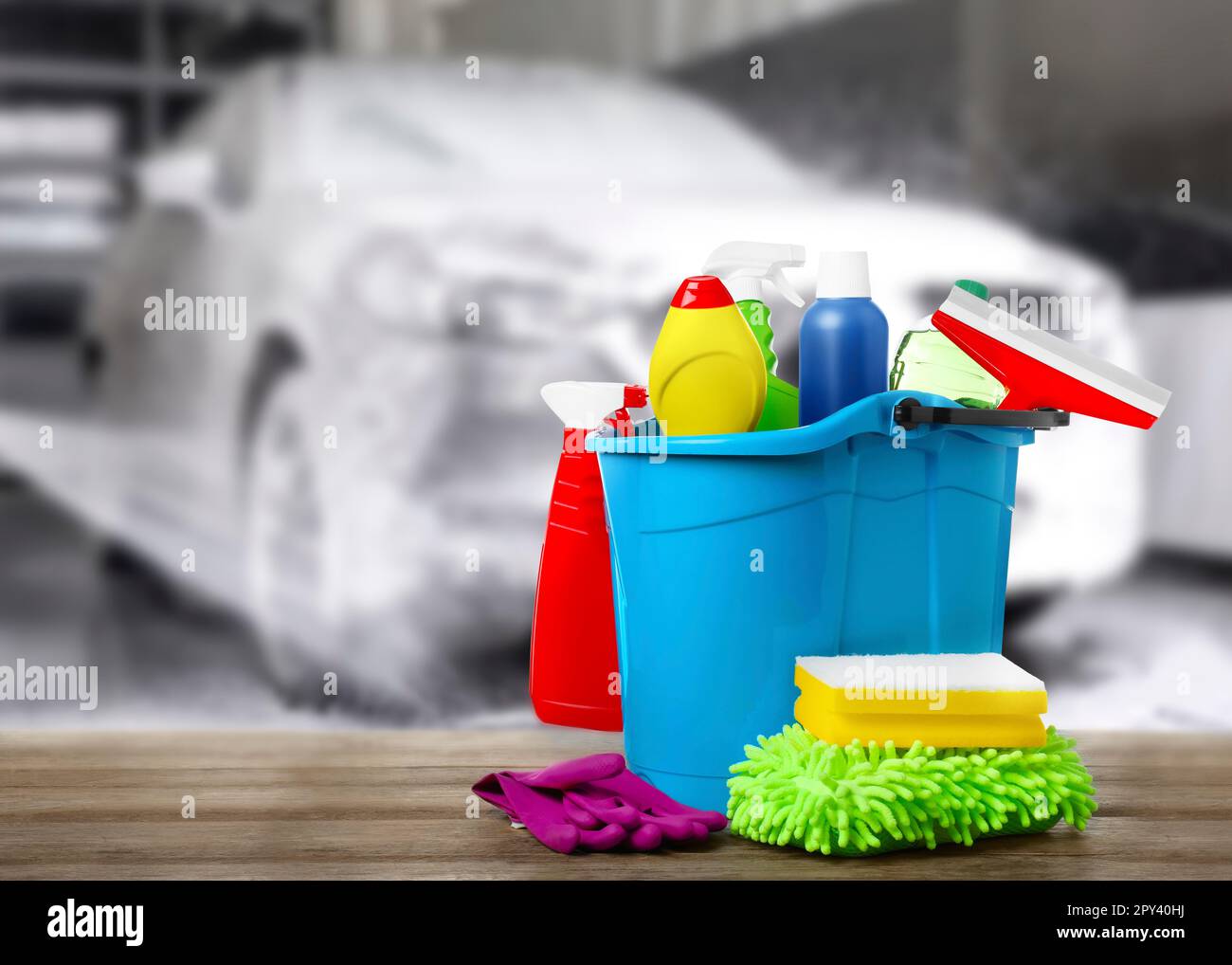 Bucket with cleaning supplies on wooden surface at car wash. Space for ...
