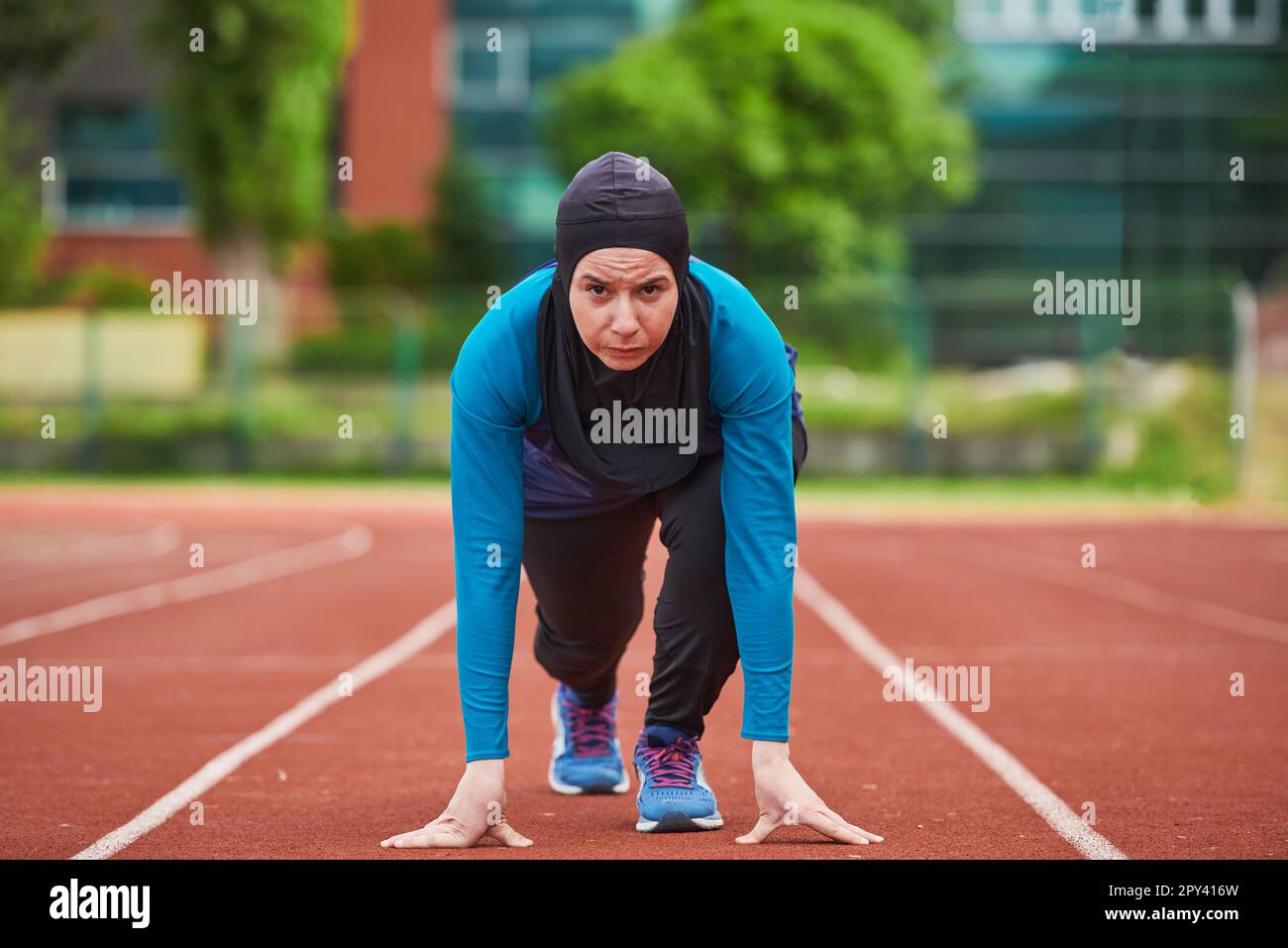 Muslim woman in burqa in sporty Muslim clothes in starting pose for ...