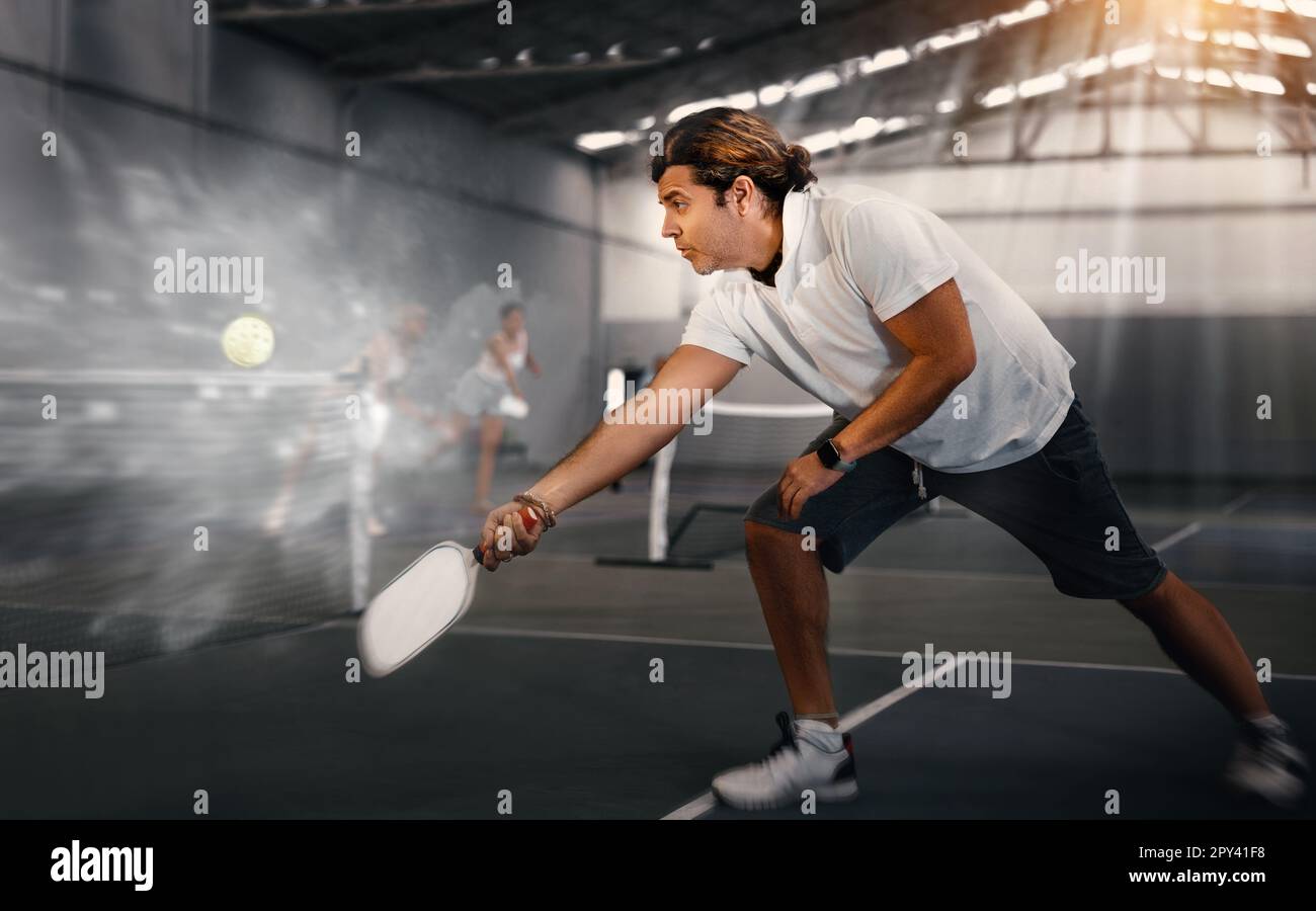 Sporty man pickleball tennis player trains on the indoor court using a ...