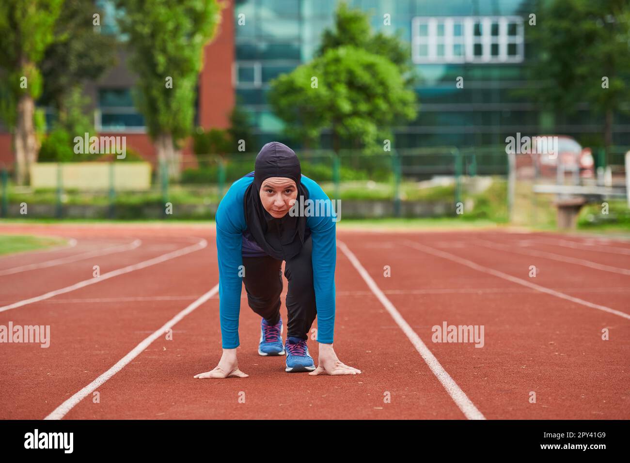 Muslim woman in burqa in sporty Muslim clothes in starting pose for ...