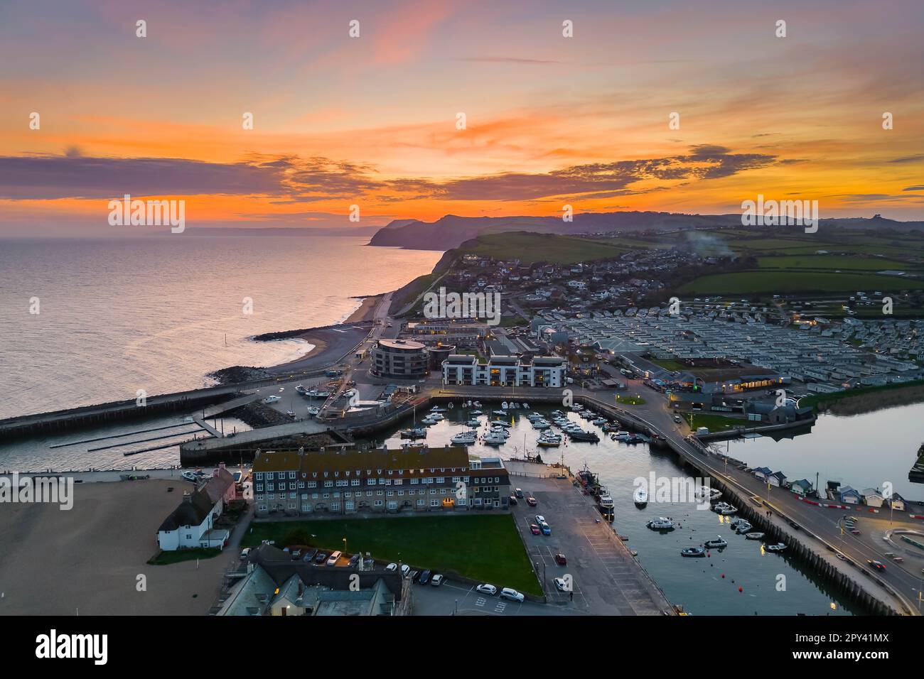 View from the air as the sky glows orange at sunset above the seaside ...