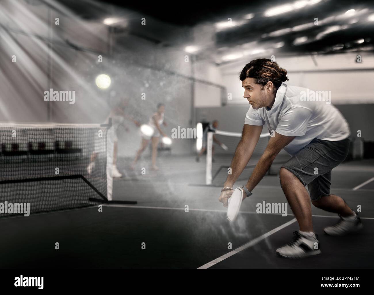 Sporty man pickleball tennis player trains on the indoor court using a ...