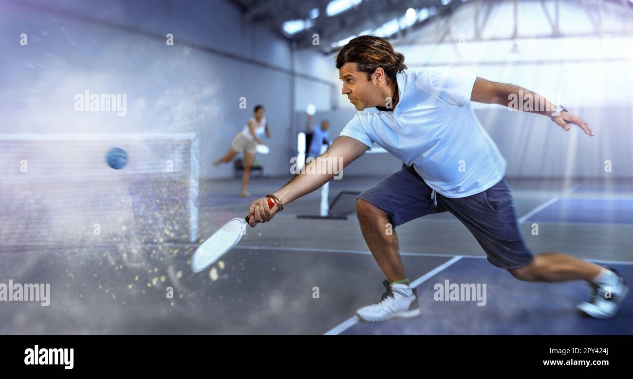 Sporty man pickleball tennis player trains on the indoor court using a ...