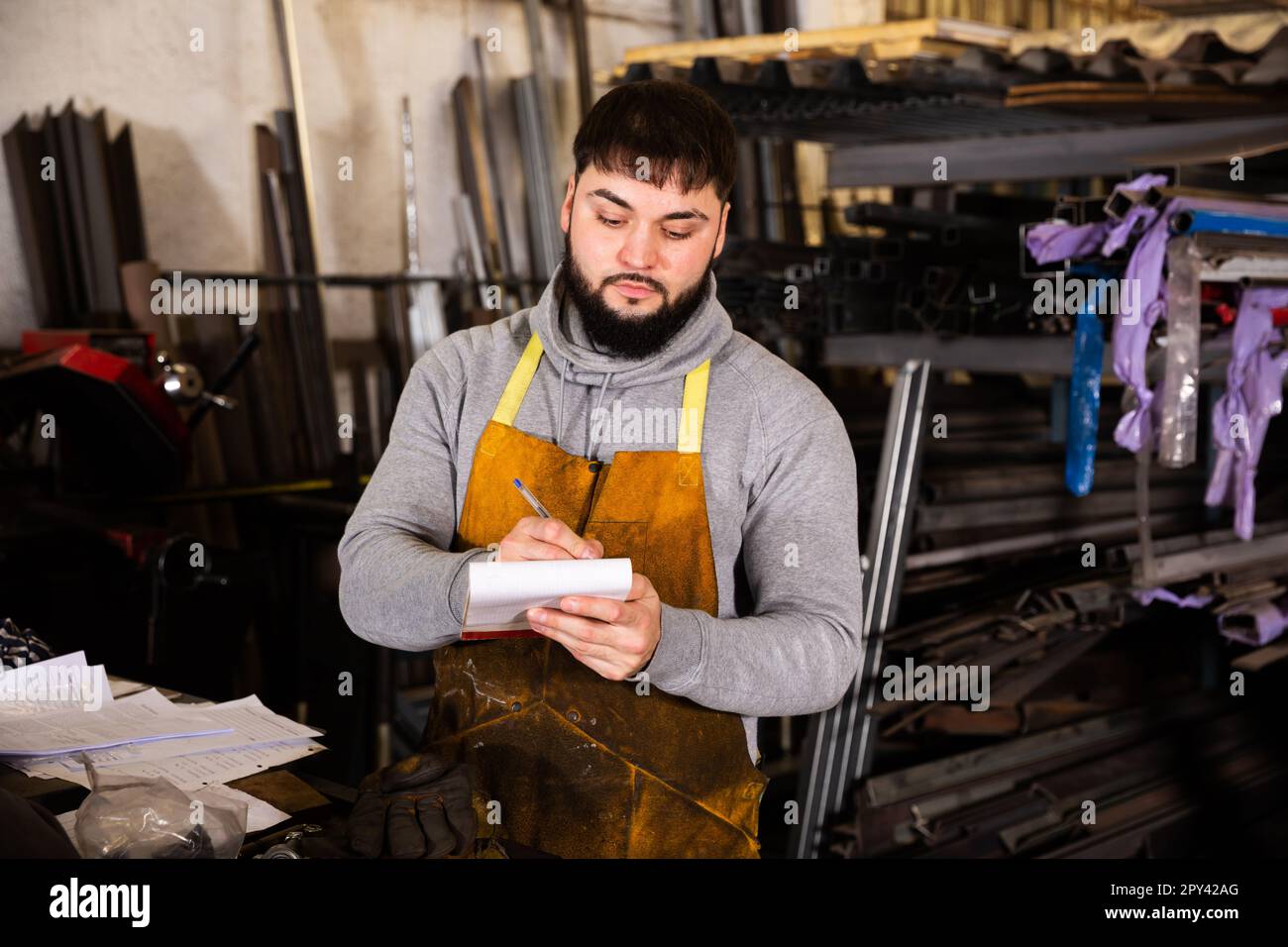 Craftsman of metalworking shop writing in notebook Stock Photo - Alamy