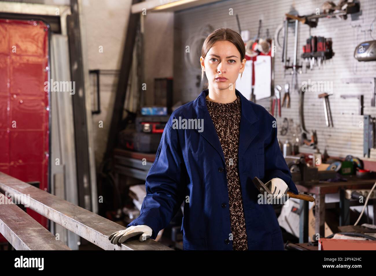 Portrait of young smiling woman in uniform who with a hammer in her ...
