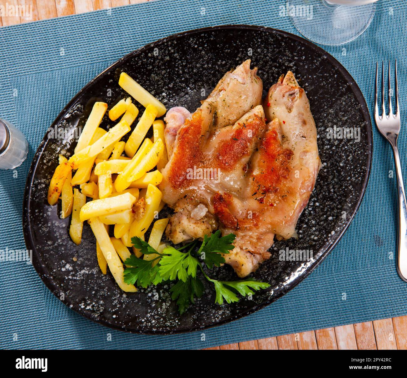 Baked spicy pig trotters with french fries and parsley Stock Photo - Alamy