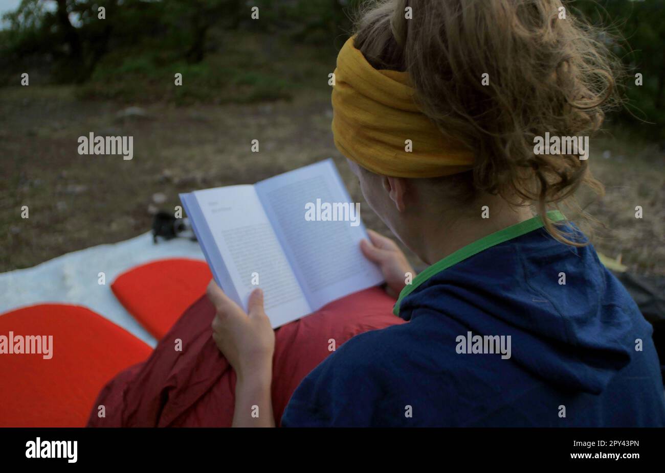 Female hiker reading book while camping Stock Photo - Alamy