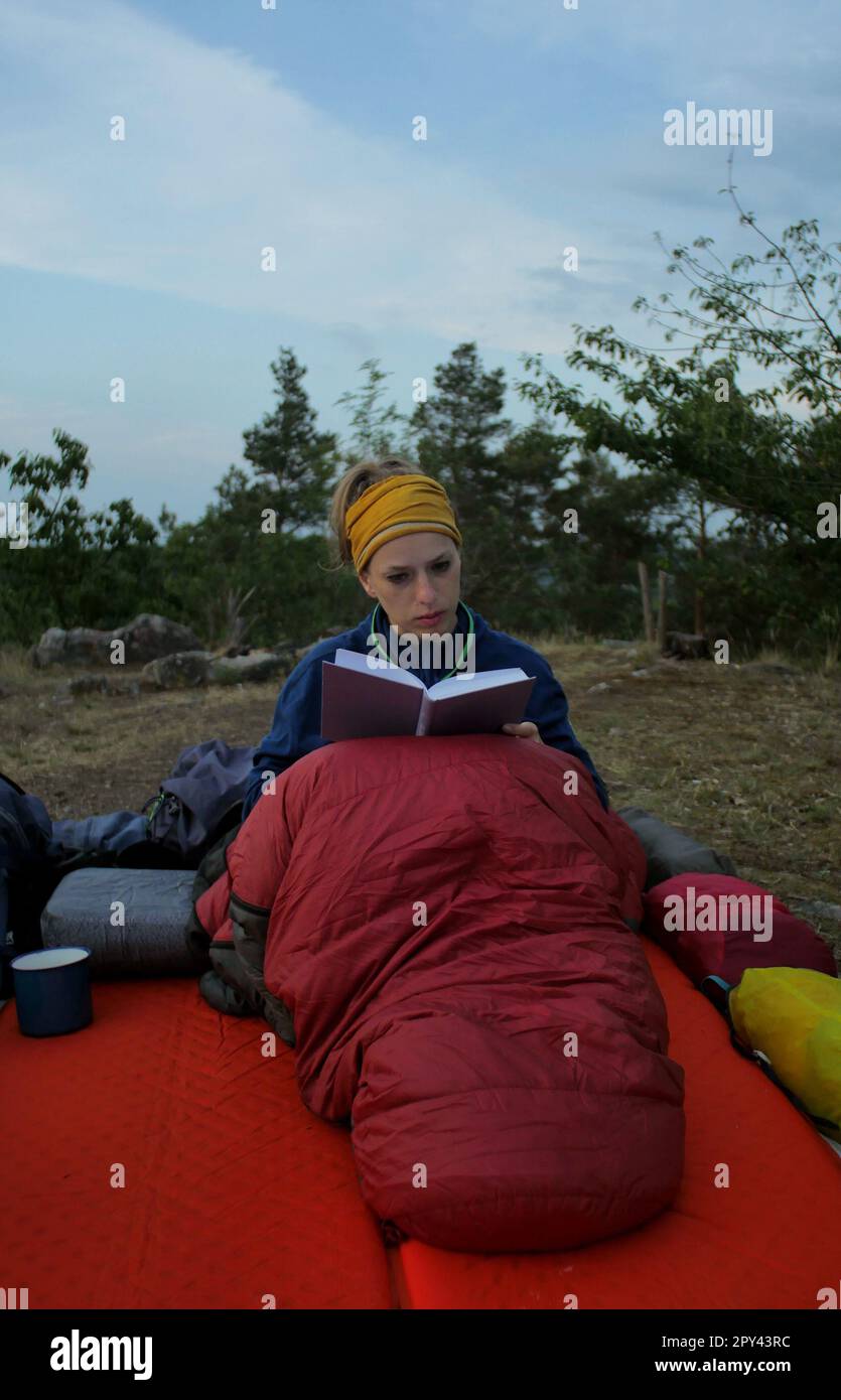 Female hiker reading book while camping Stock Photo - Alamy