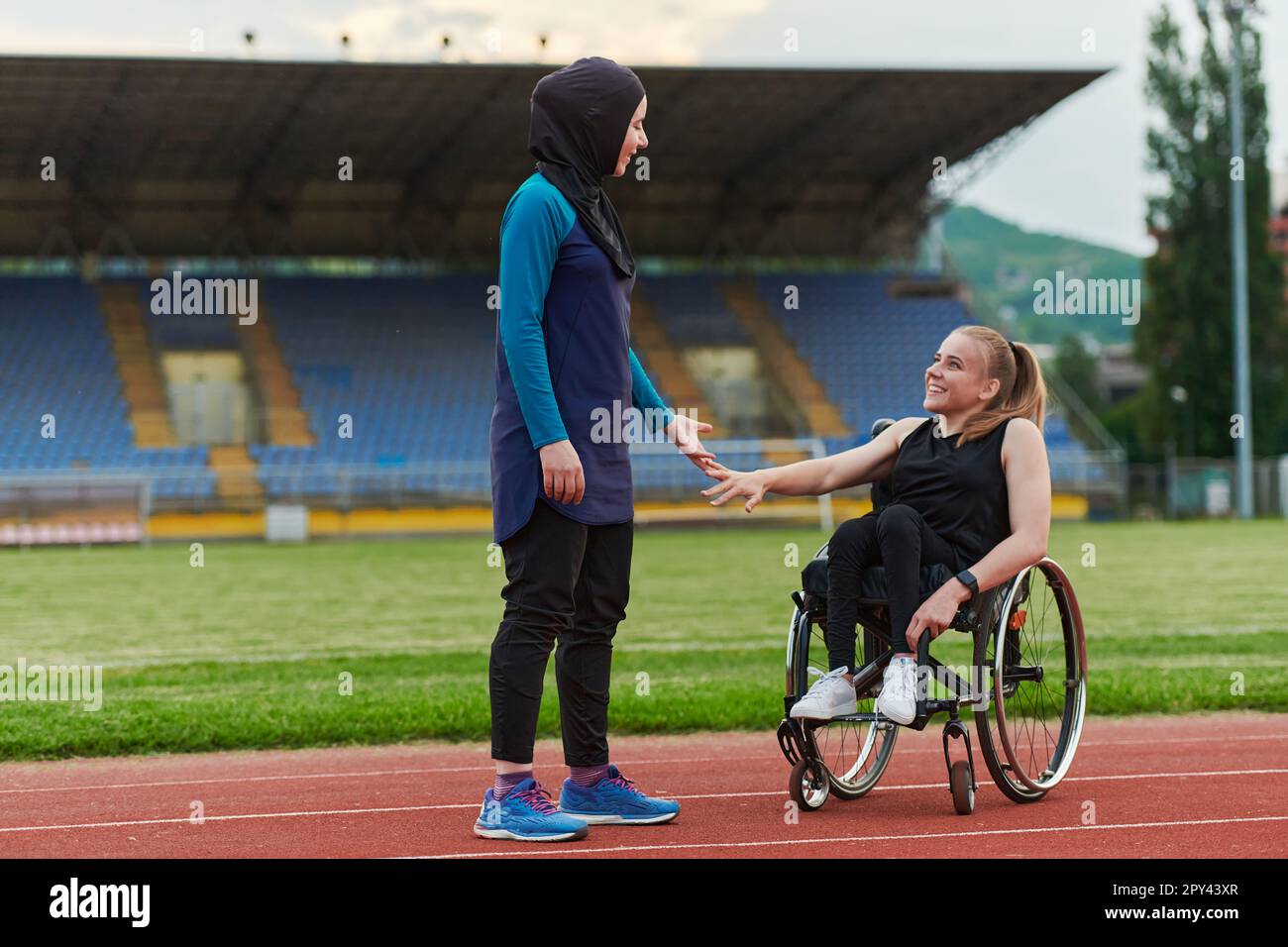 A Muslim woman wearing a burqa supports her friend with disability in a ...