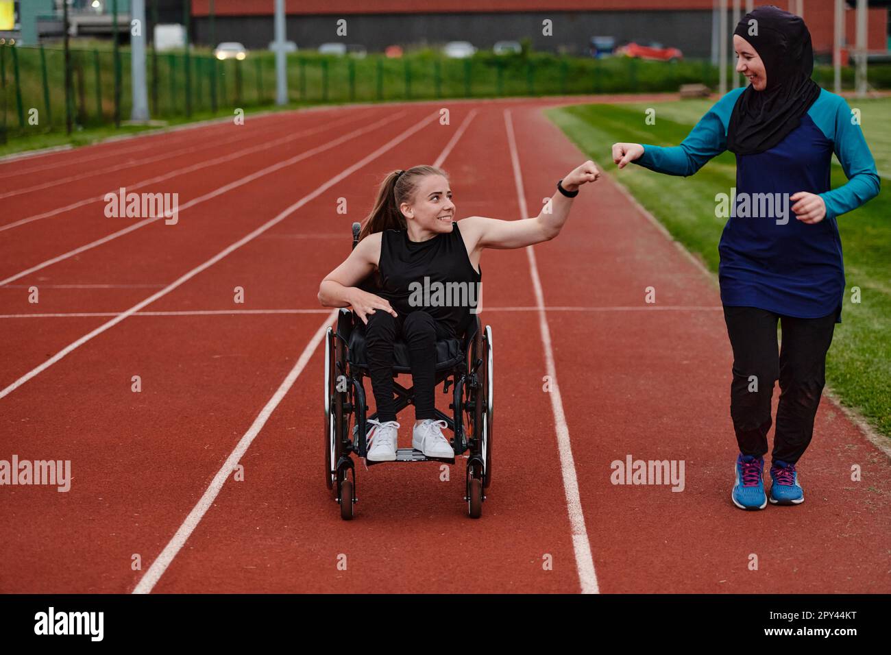 A Muslim woman wearing a burqa supports her friend with disability in a ...