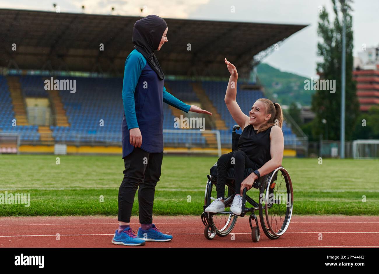 A Muslim woman wearing a burqa supports her friend with disability in a ...