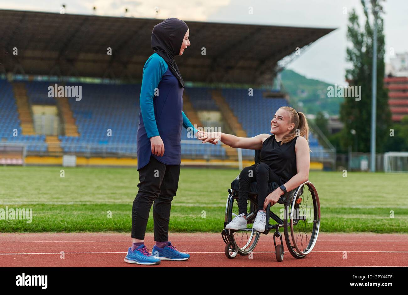 A Muslim woman wearing a burqa supports her friend with disability in a ...