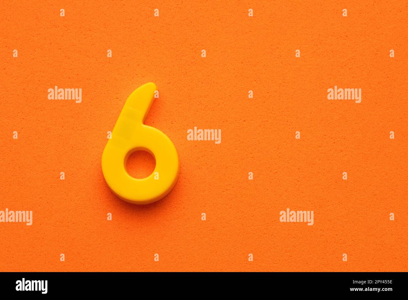 Number six yellow plastic - plastic digit on orange foamy background ...