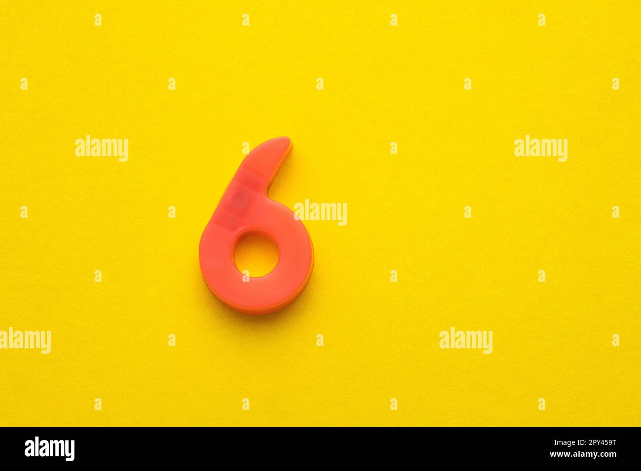 Peach colored number six (6) - plastic digit on yellow foamy background ...