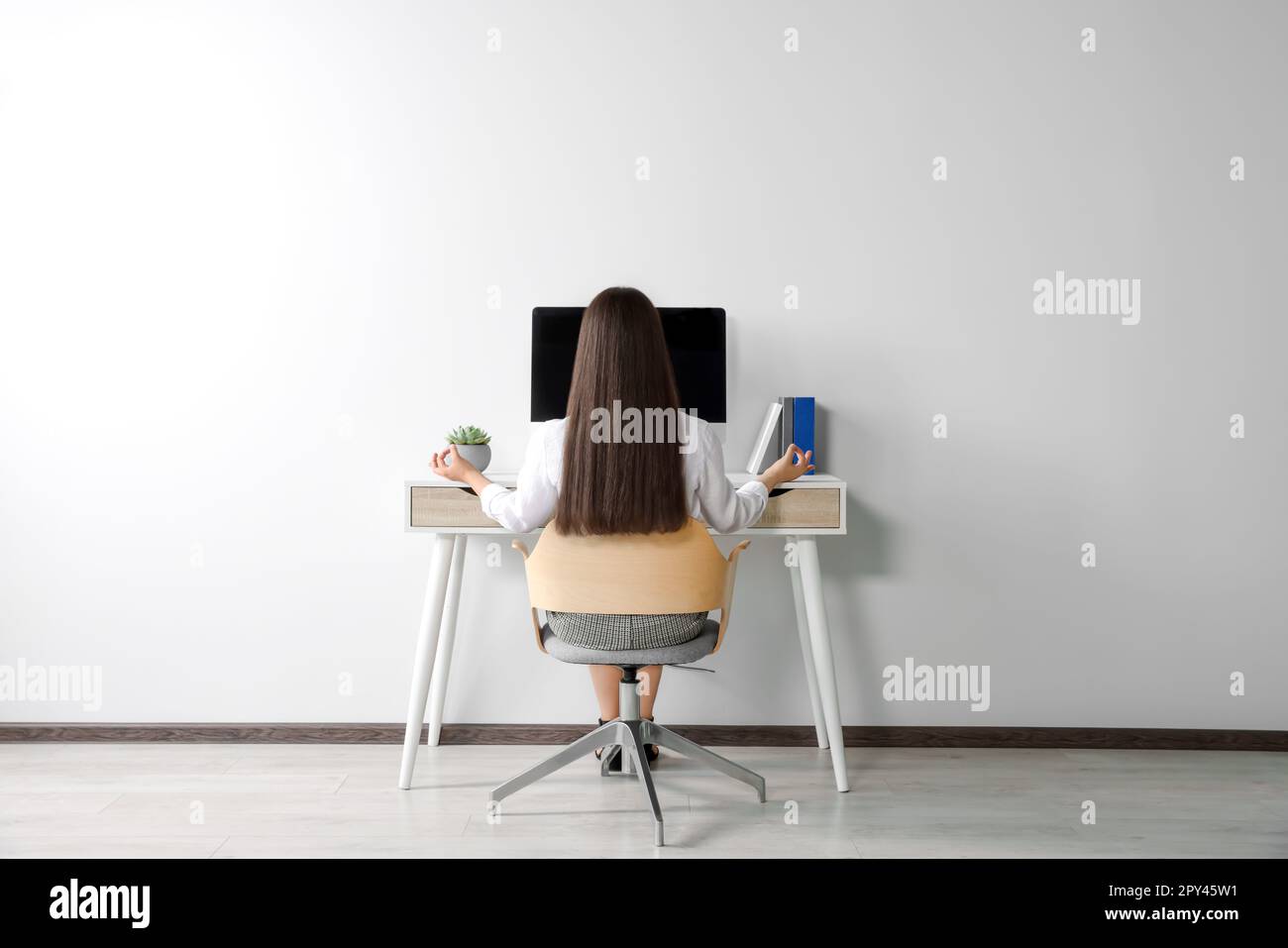 Find zen. Woman taking break from work at table in room, back view ...