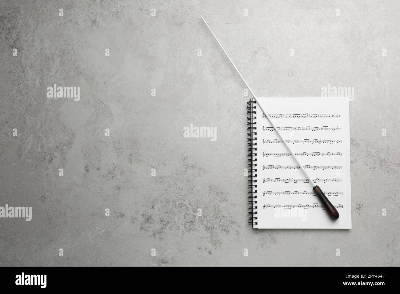 Conductor's baton and sheet music book on grey background, top view ...