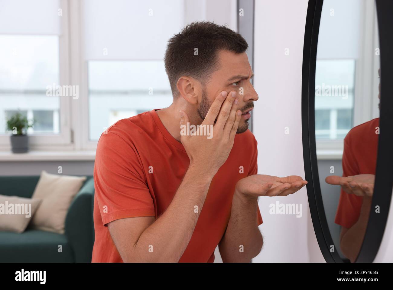 Sleep deprived man looking at himself in mirror indoors Stock Photo - Alamy