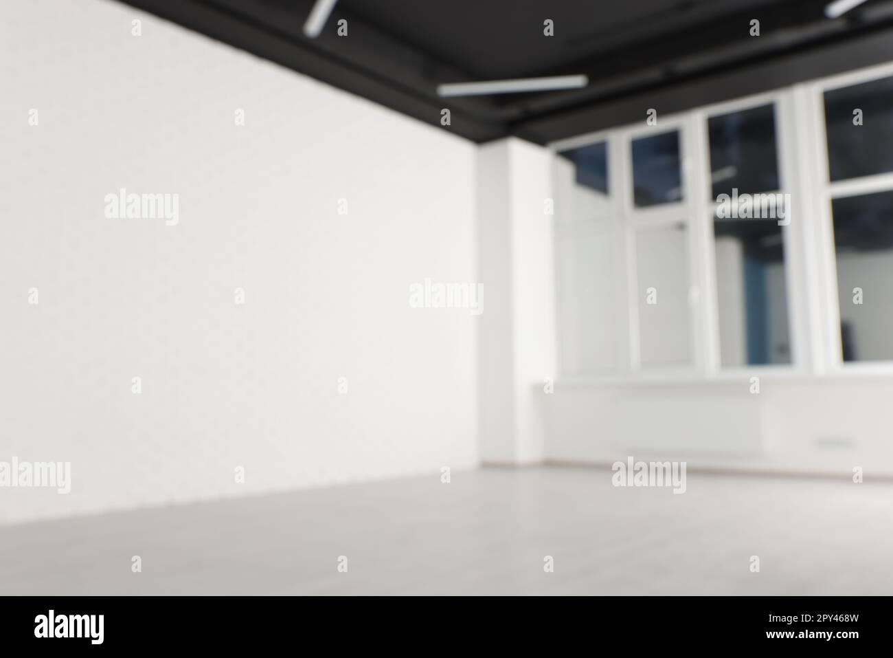 Blurred view of empty office room with black ceiling and windows ...