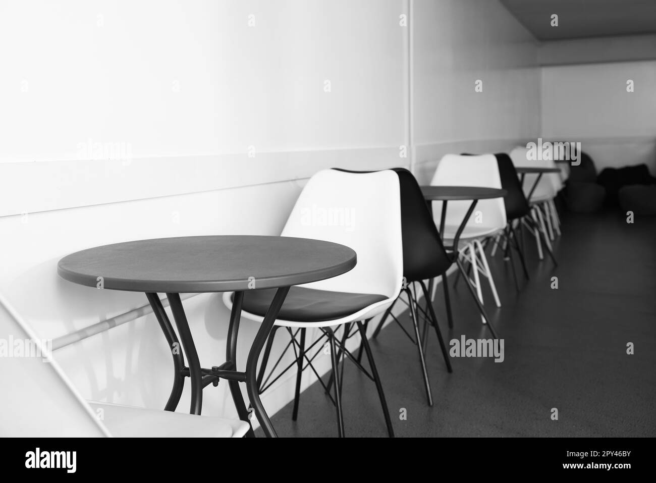 Hostel dining room interior with tables and chairs along white wall ...