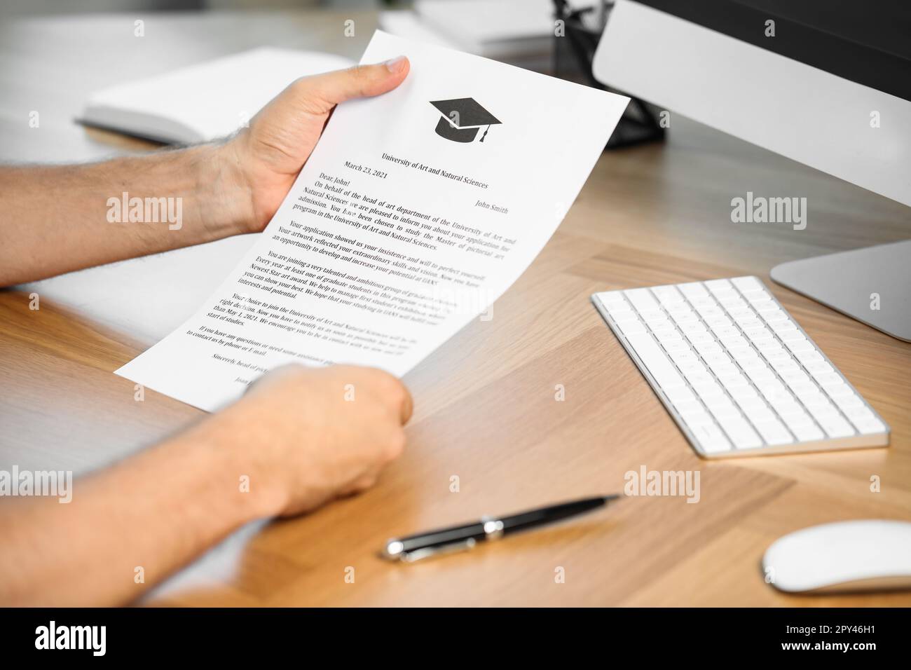 Student with acceptance letter from university at wooden table indoors ...