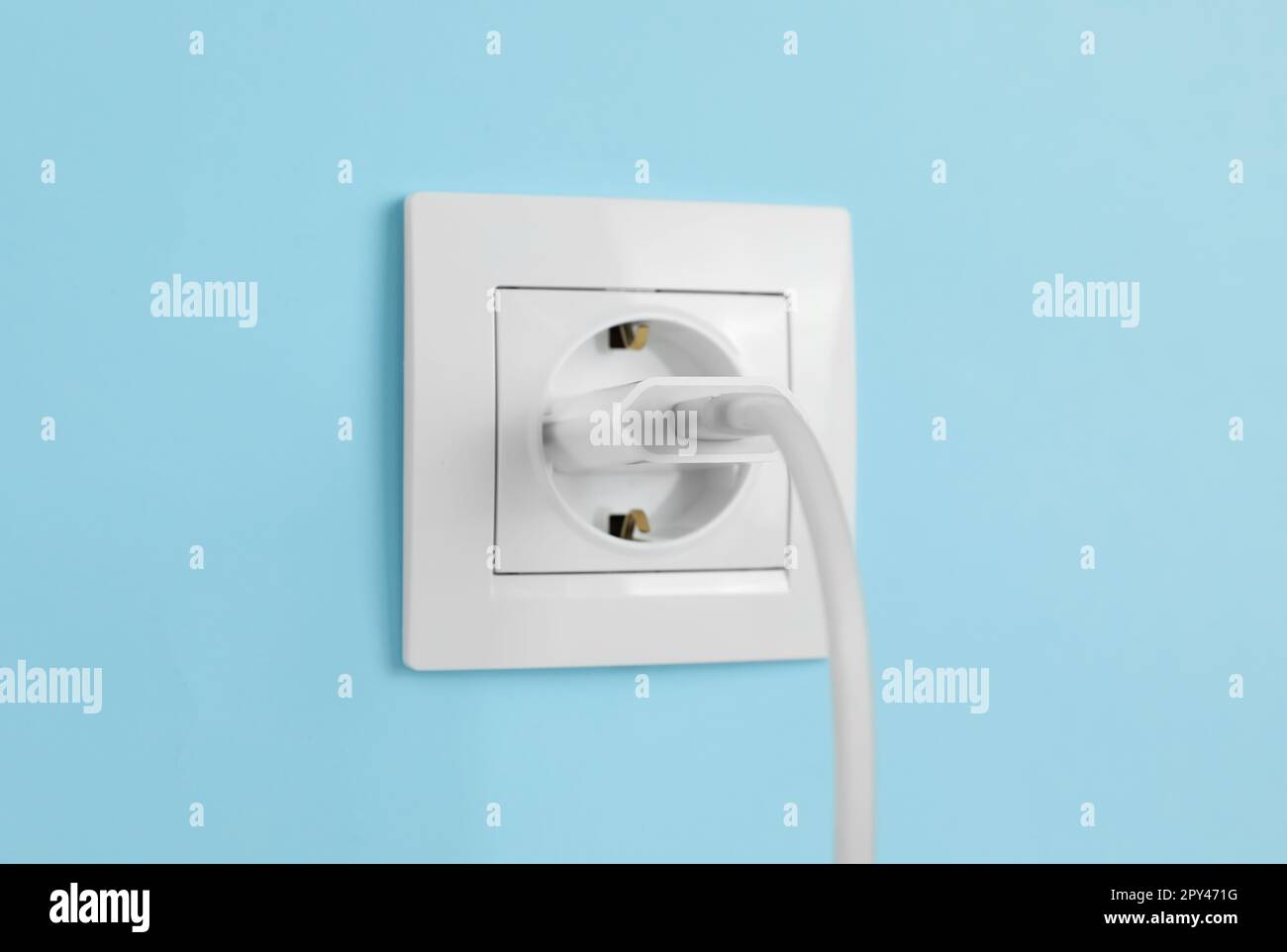 Charger adapter plugged into power socket on light blue wall ...