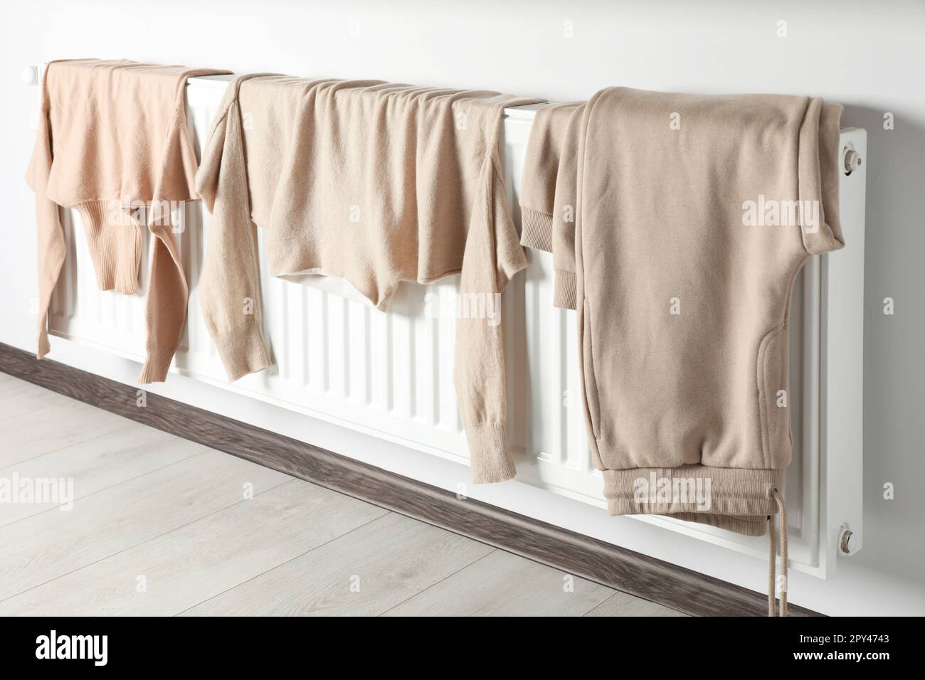 Clean clothes hanging on white radiator in room Stock Photo - Alamy