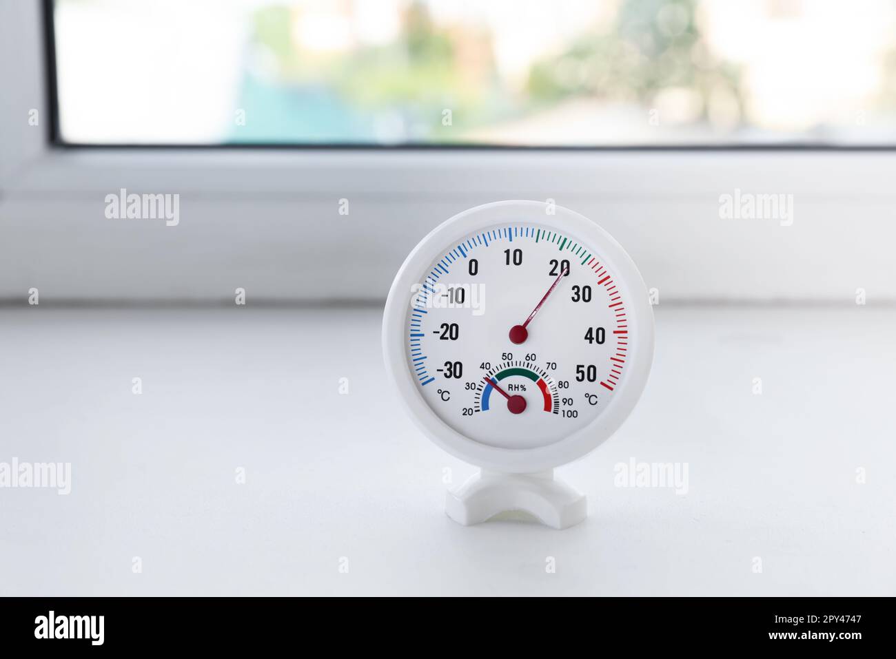 Round hygrometer with thermometer on window sill indoors Stock Photo ...