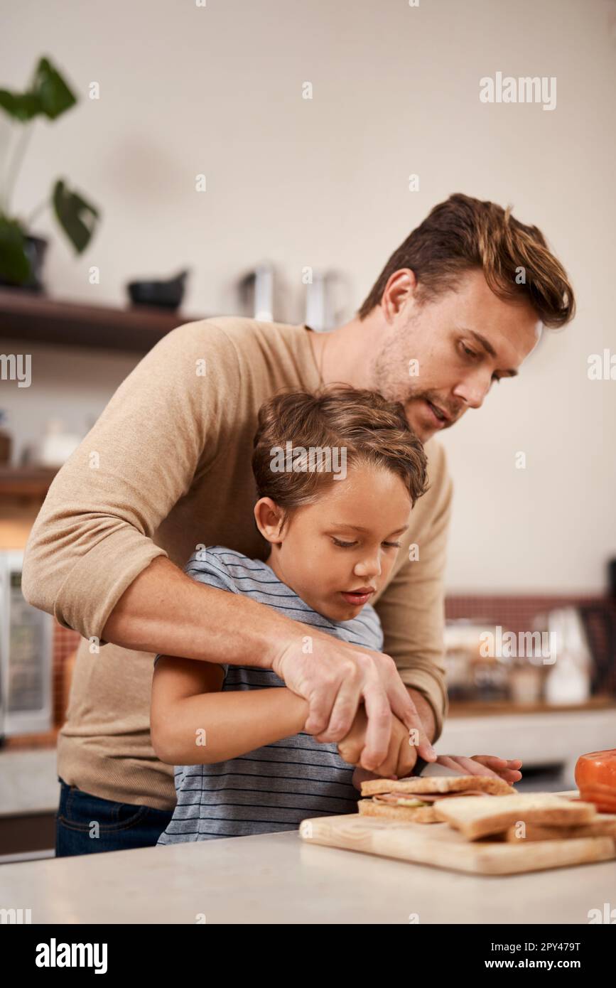 Getting lunch ready. a young boy making a sandwich with the help of his ...