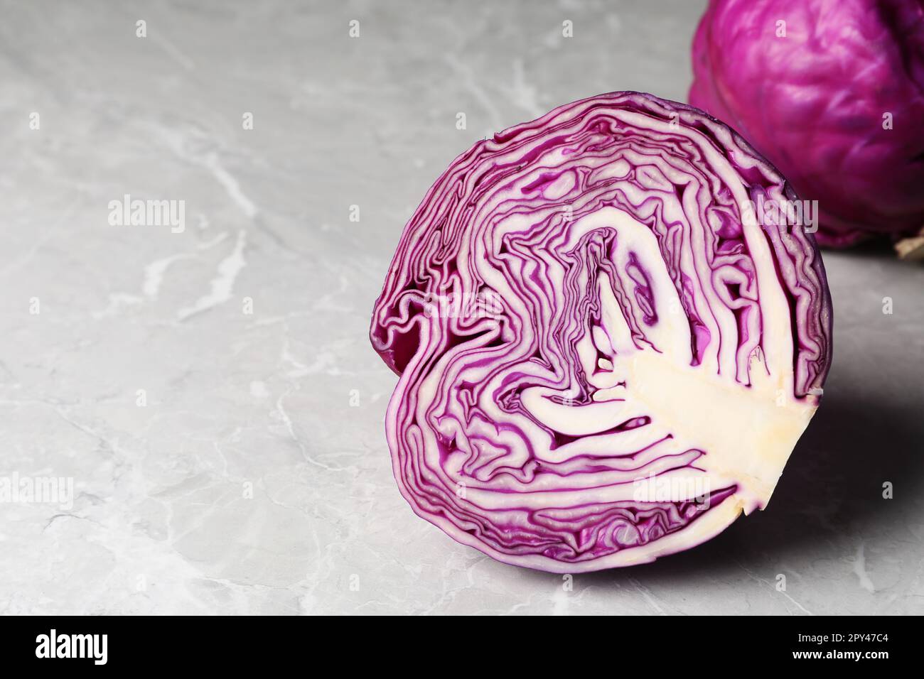 Half of fresh red cabbage on light grey marble table, space for text ...
