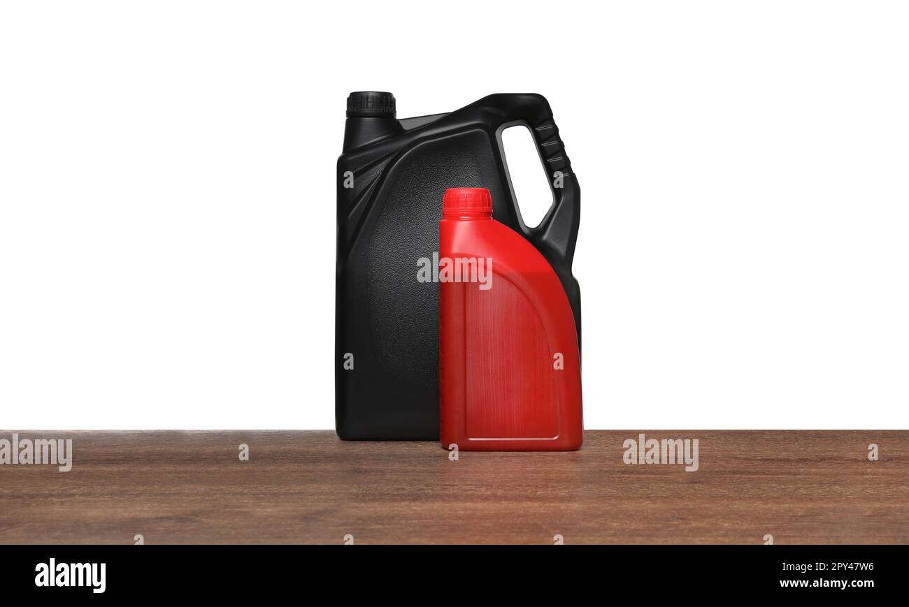 Motor oil in different containers on wooden table against white ...