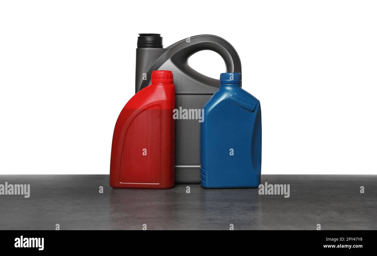 Motor oil in different containers on grey table against white ...