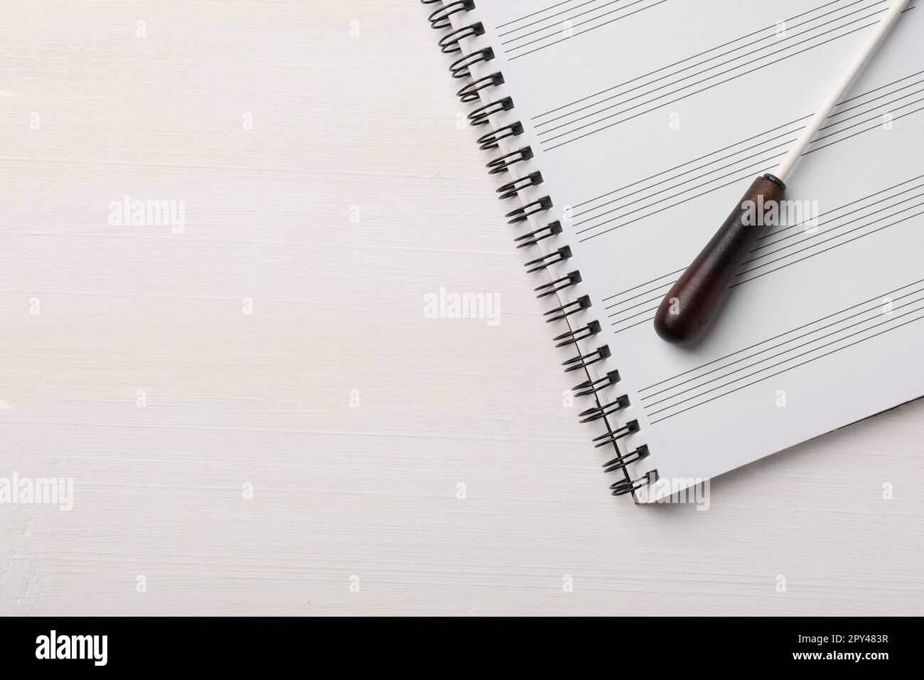 Conductor's baton and sheet music book on white wooden table, top view ...