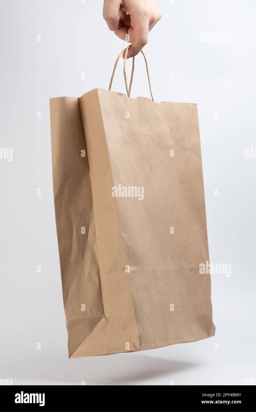 Cardboard paper bag hang on one finger isolated on white studio ...