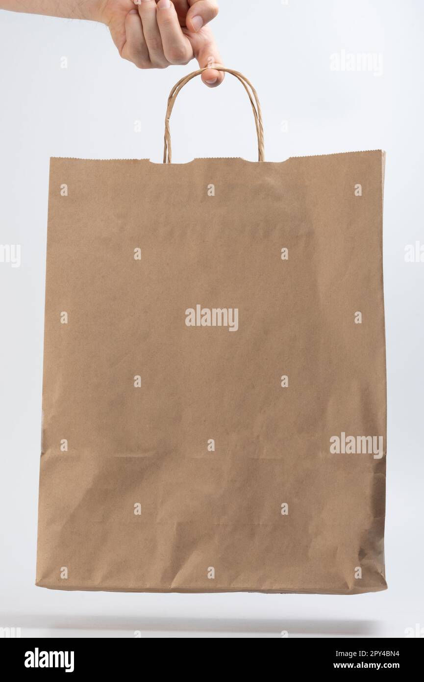 Hand hold paper recycled bag with one finger isolated on white studio ...