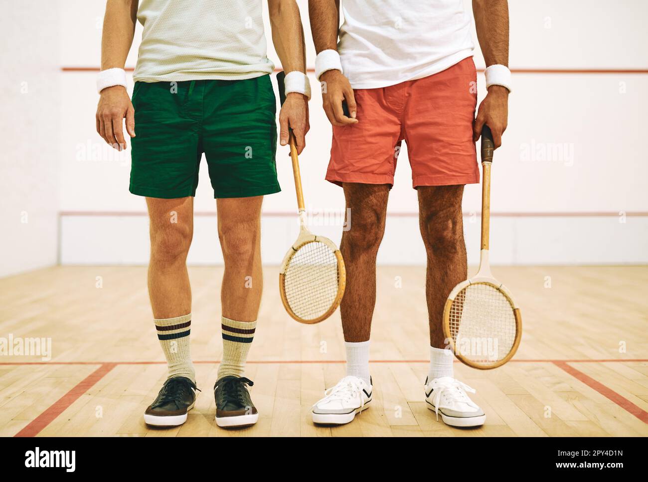 Vintage style for a game of squash. two men holding their racquets at a ...