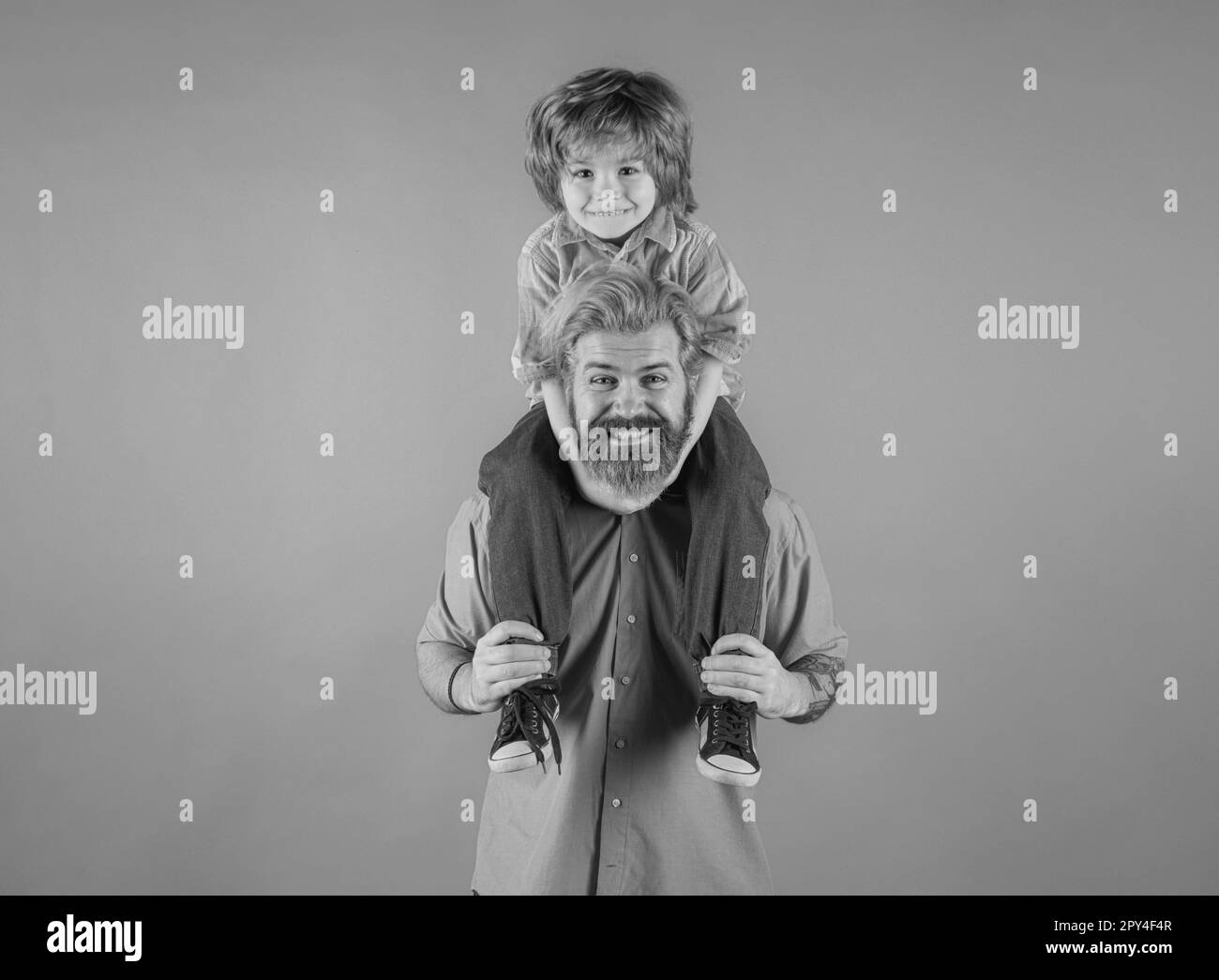 Father giving piggyback ride to his son against a green studio ...