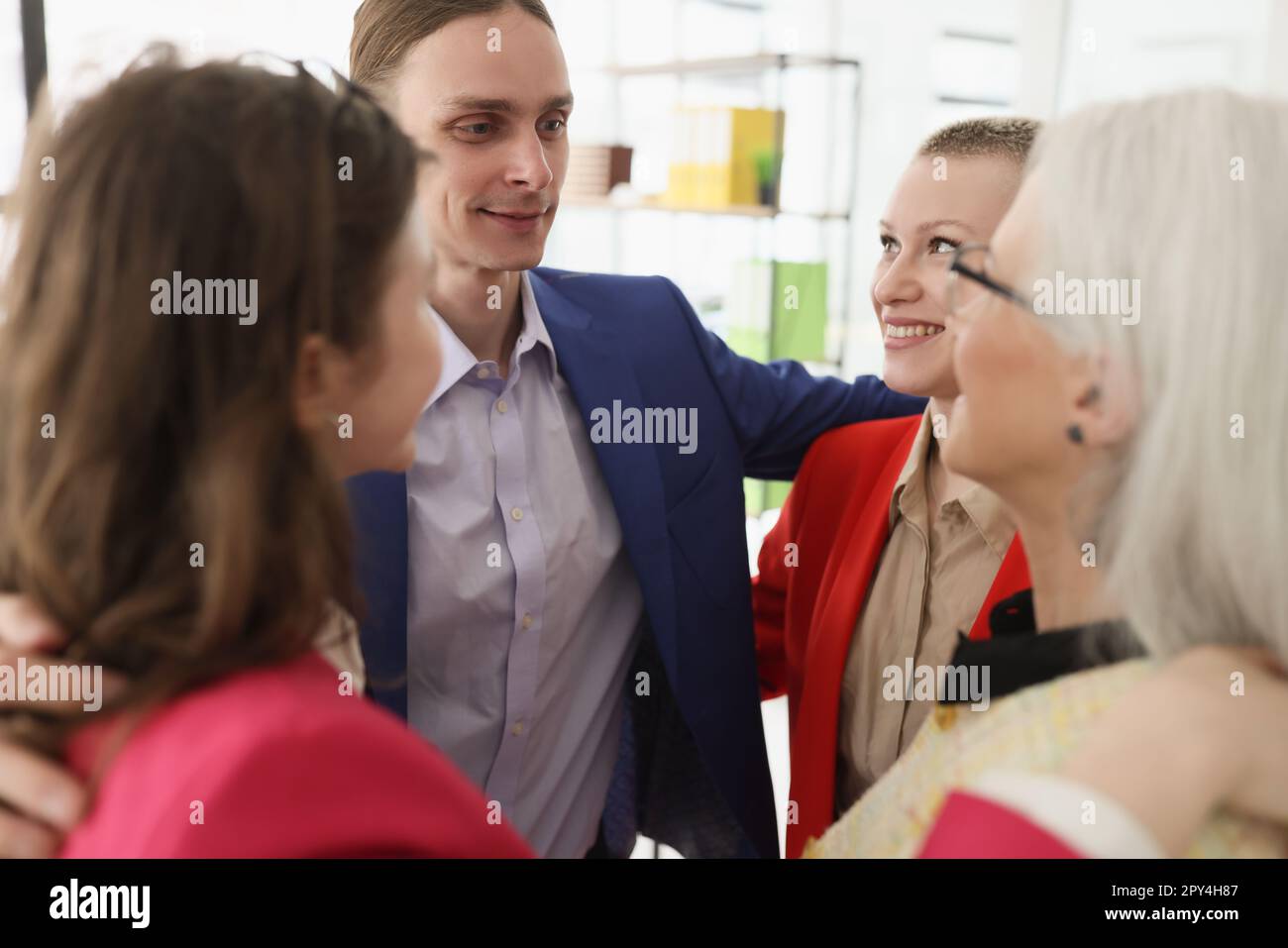 Young man hugs female colleagues congratulating with success Stock ...