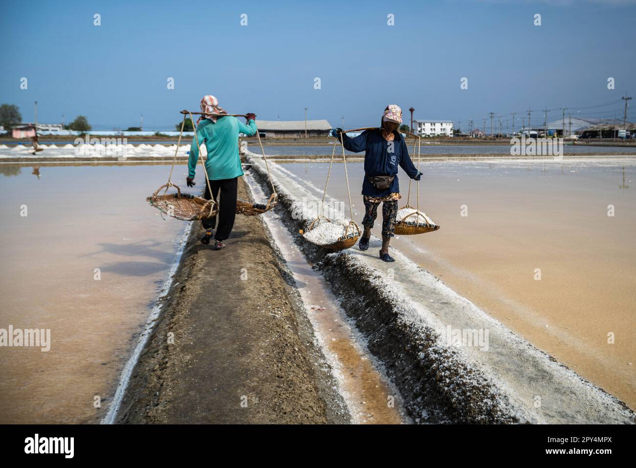 Ban Laem, Thailand. 25th Apr, 2023. Salt workers carry backsets full of ...